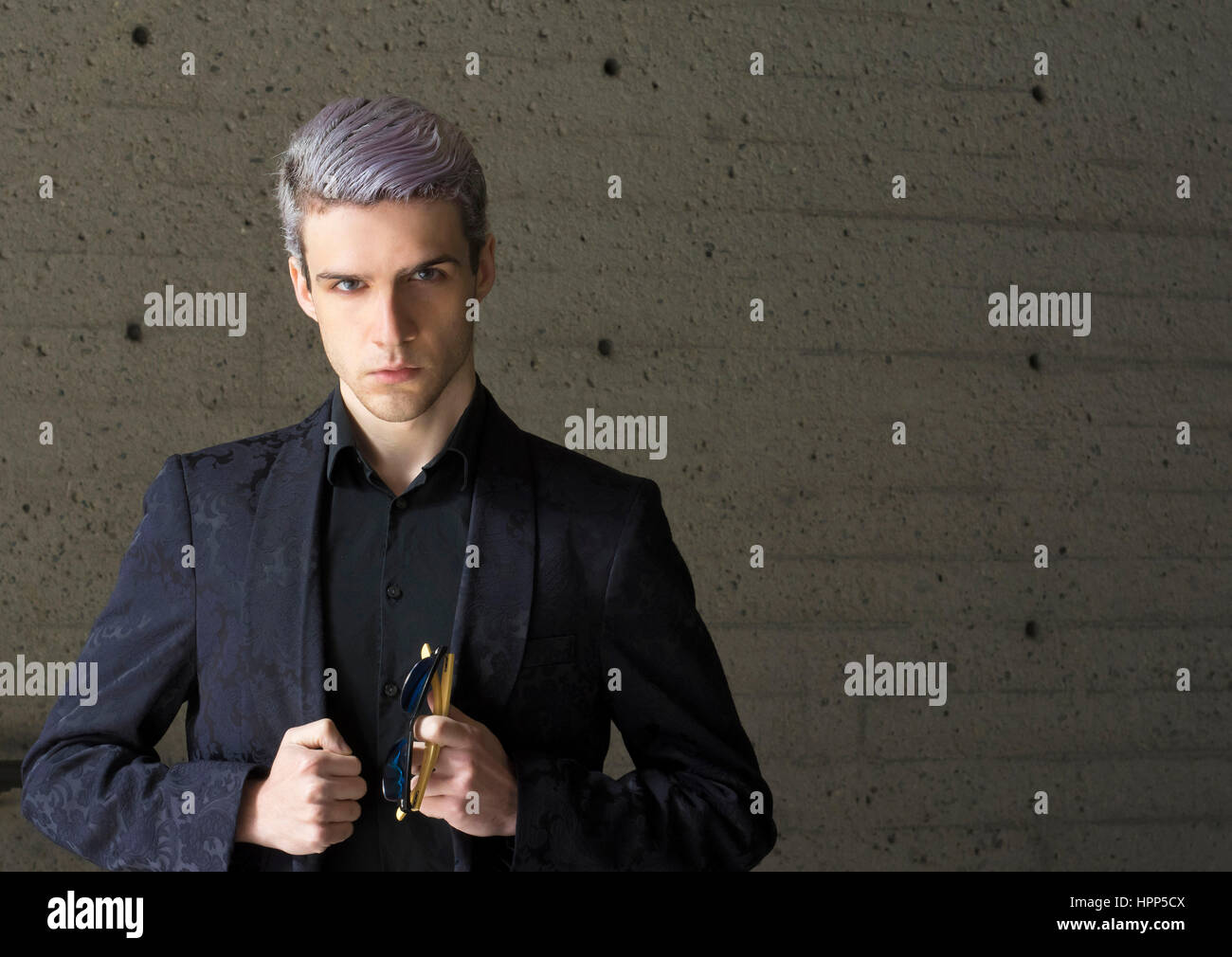 Young determined man wearing suit with concrete background, side lit ...