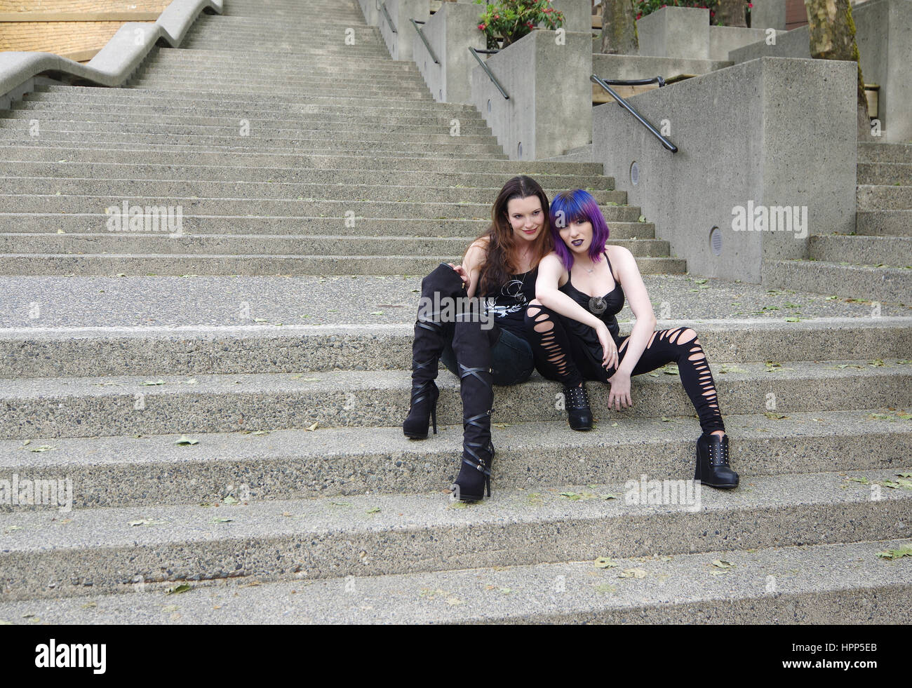 two alternative punk women sitting on stairs smiling, wearing black ...