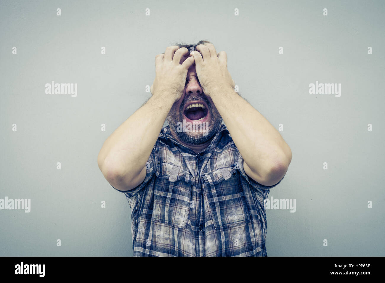portrait one sad man standing near a wall and covers his face at the ...