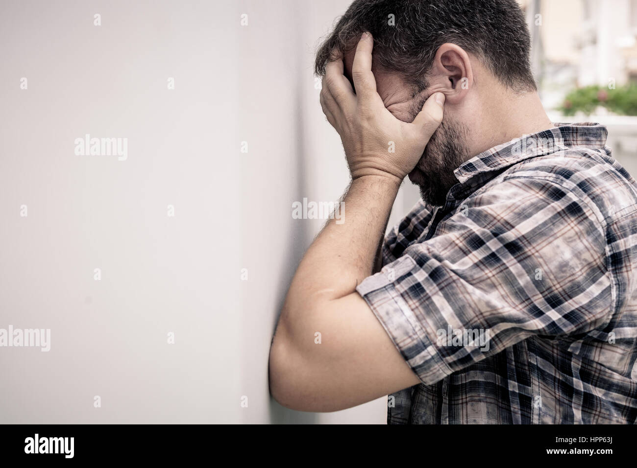 portrait one sad man standing near a wall and covers his face at the ...