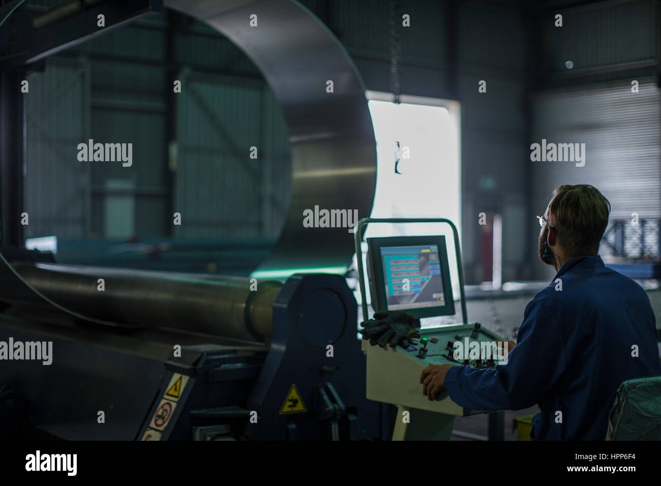 Worker operating machinery at control panel in steel factory Stock ...