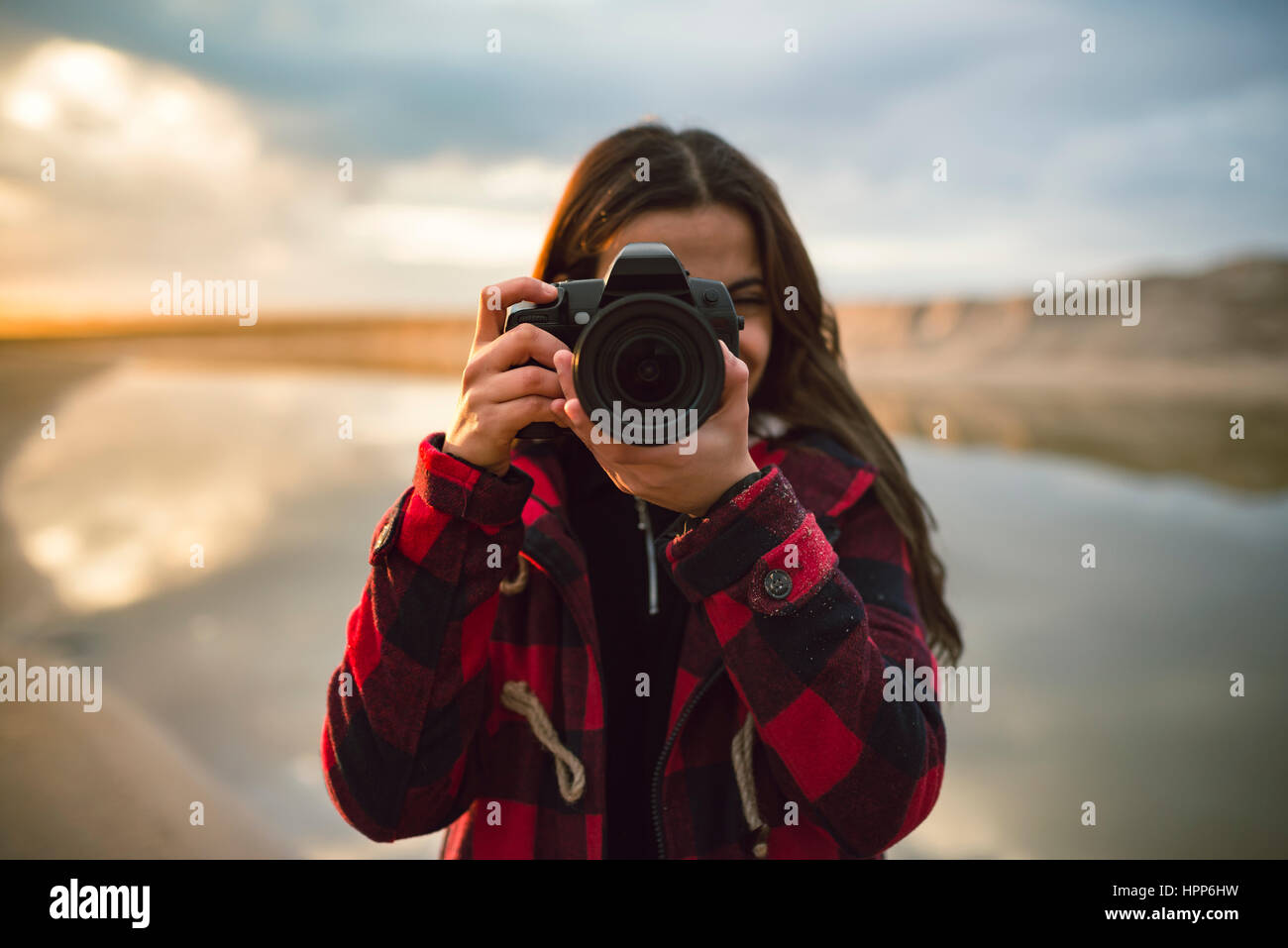 Young woman taking picture with camera on the beach Stock Photo - Alamy