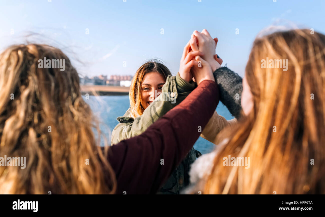 Four happy friends raising their hands together Stock Photo - Alamy