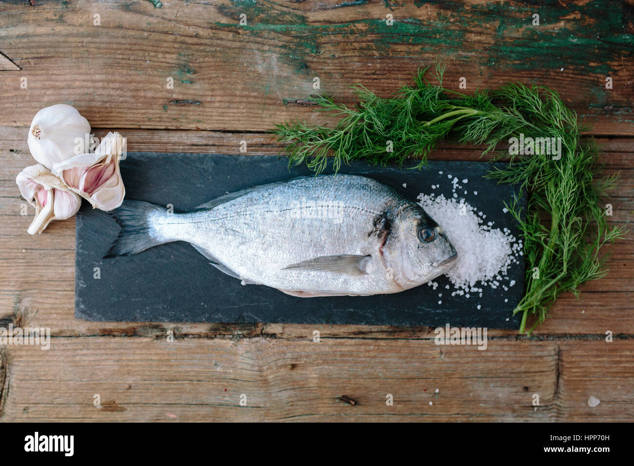Sea Bream on a slate board with dill and salt and garlic Stock Photo ...