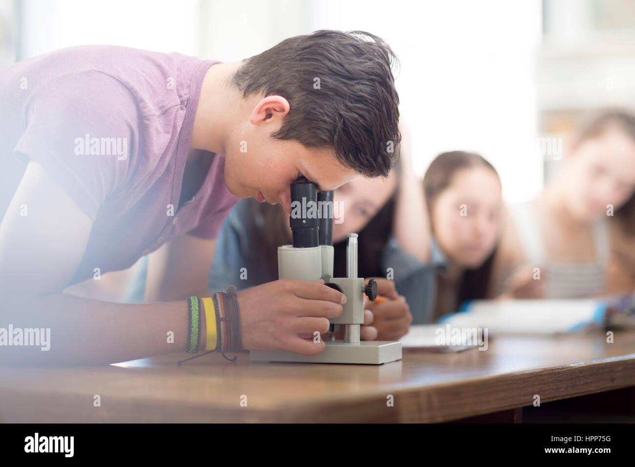Science student in class looking through microscope Stock Photo - Alamy