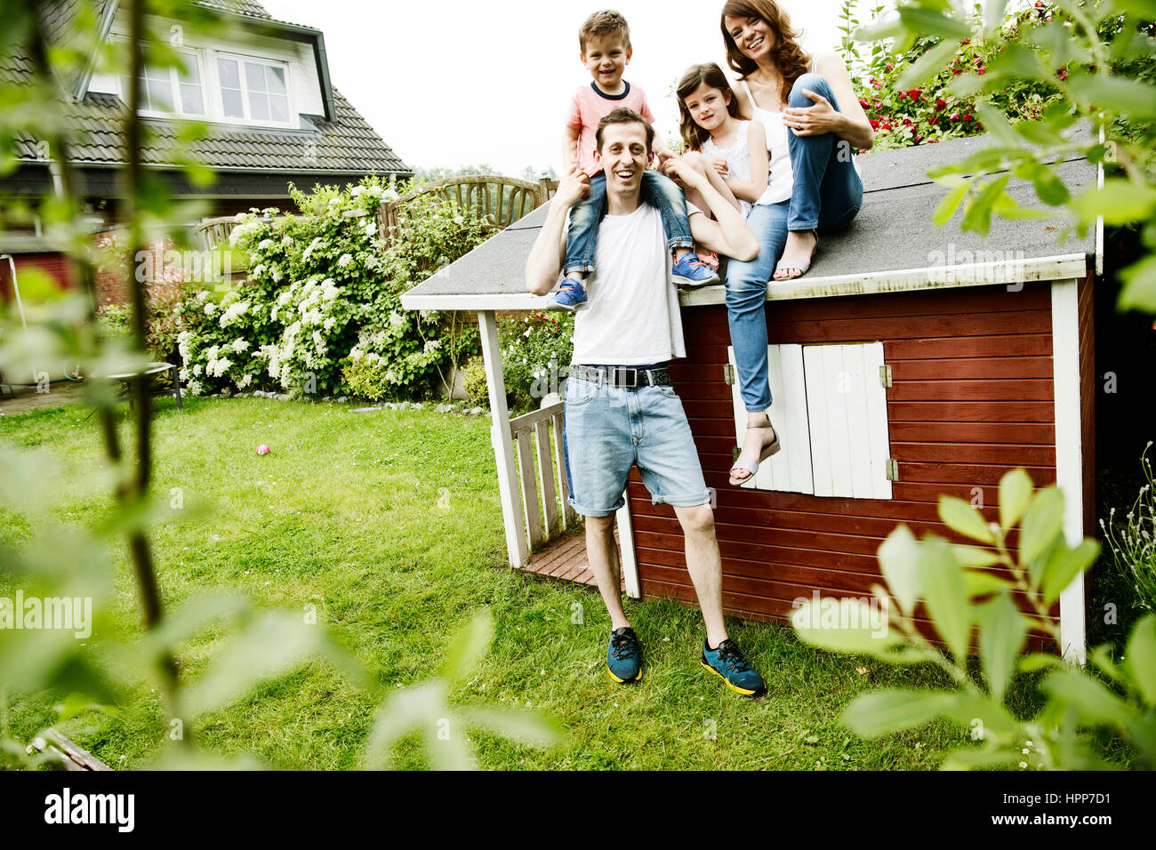 Happy family sitting on roof of their garden shed Stock Photo - Alamy