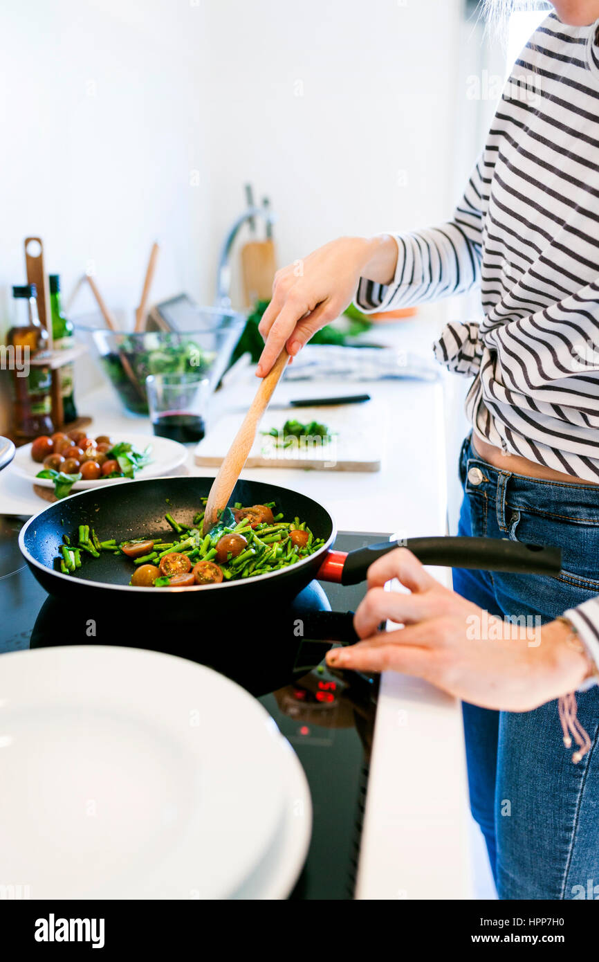 Young woman cooking vegan pasta in her kitchen Stock Photo - Alamy