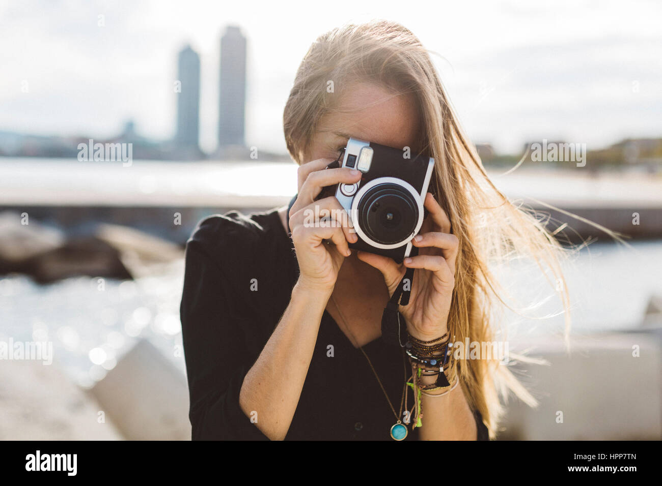 Young woman taking picture with old-fashioned camera at the seafront ...