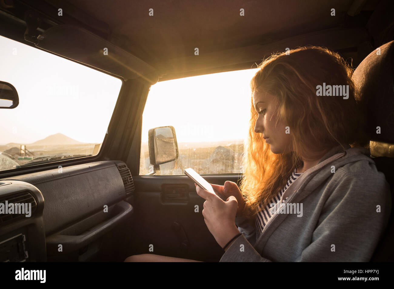 Woman in car looking at cell phone Stock Photo - Alamy