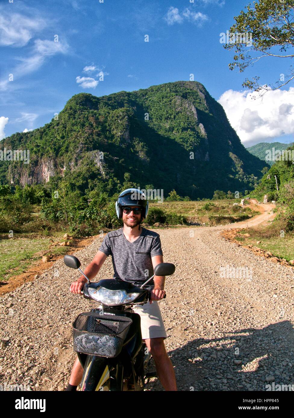 White caucasian male man riding a motor bike over a dirt path in front ...