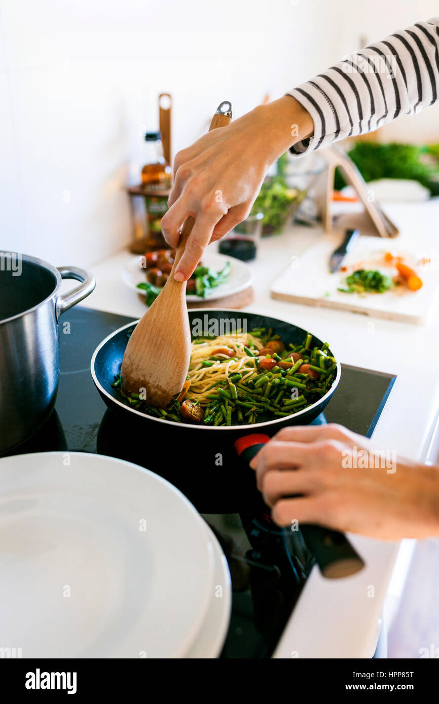Young woman cooking vegan pasta in her kitchen Stock Photo - Alamy
