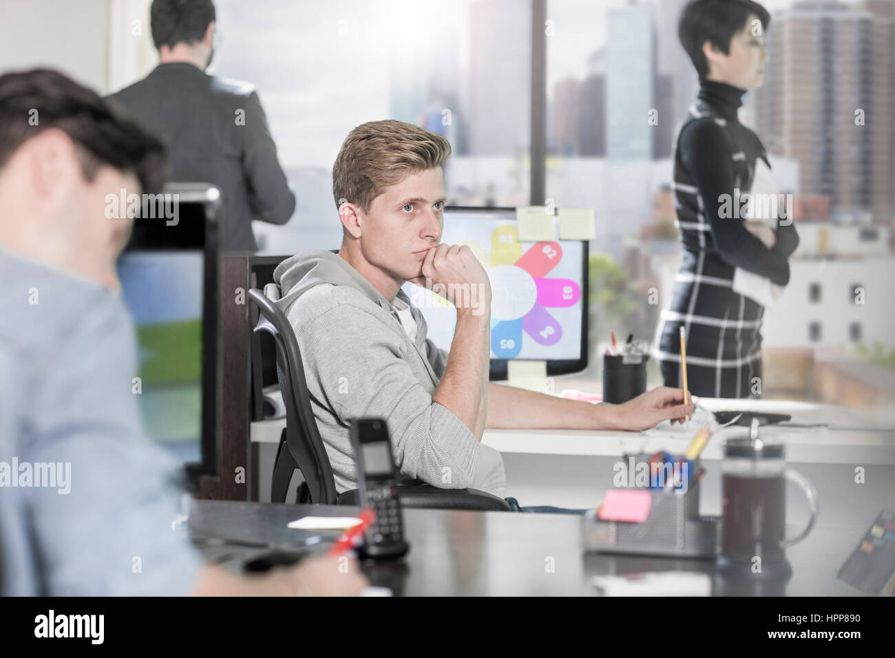 Young man at office desk thinking Stock Photo - Alamy