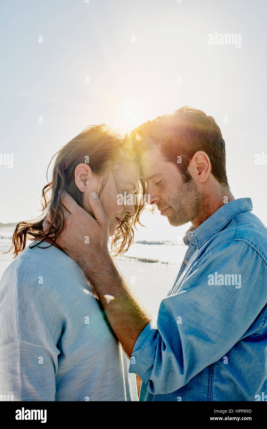 Couple head to head on the beach at backlight Stock Photo - Alamy