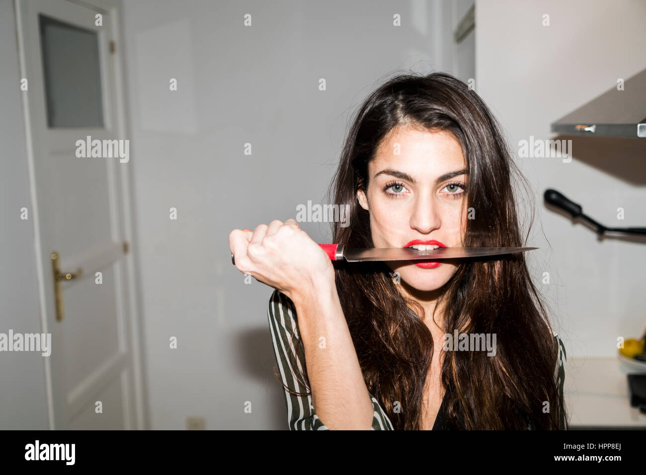 Portrait of woman with kitchen knife between her teeth Stock Photo - Alamy