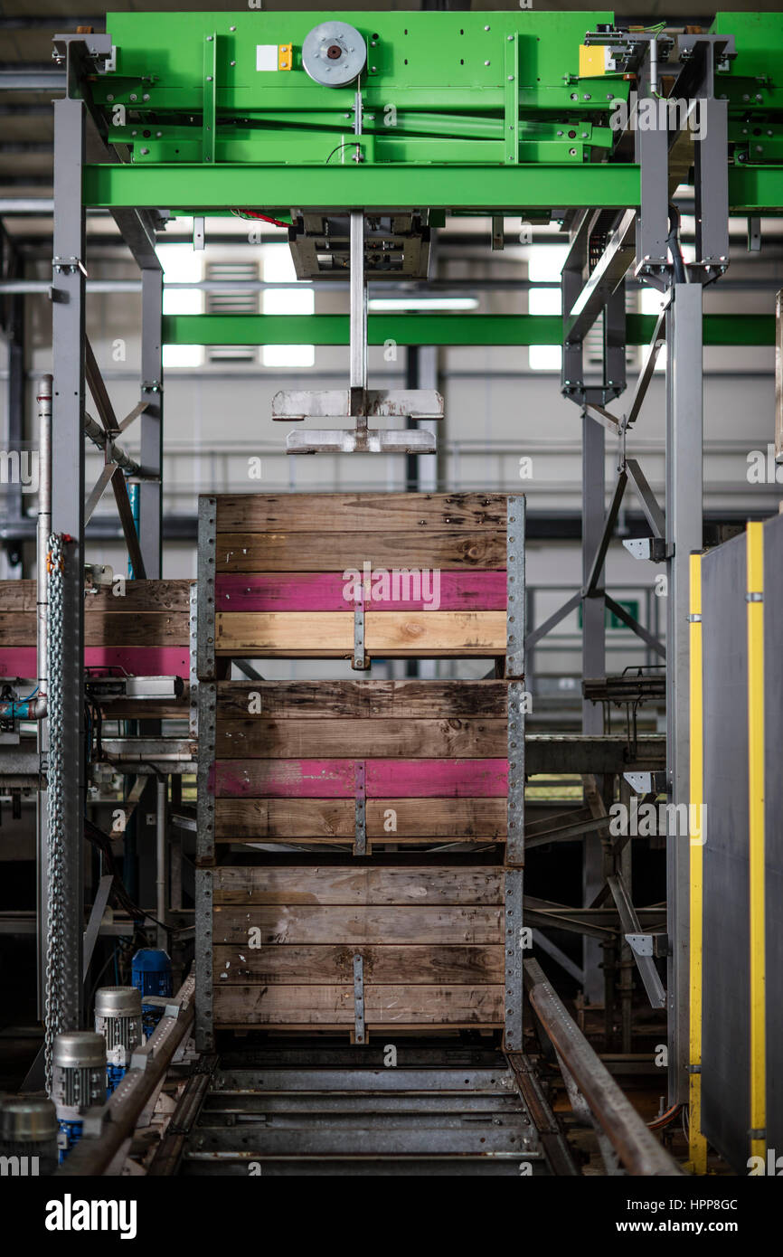Group of crates stacked on machine in factory Stock Photo - Alamy