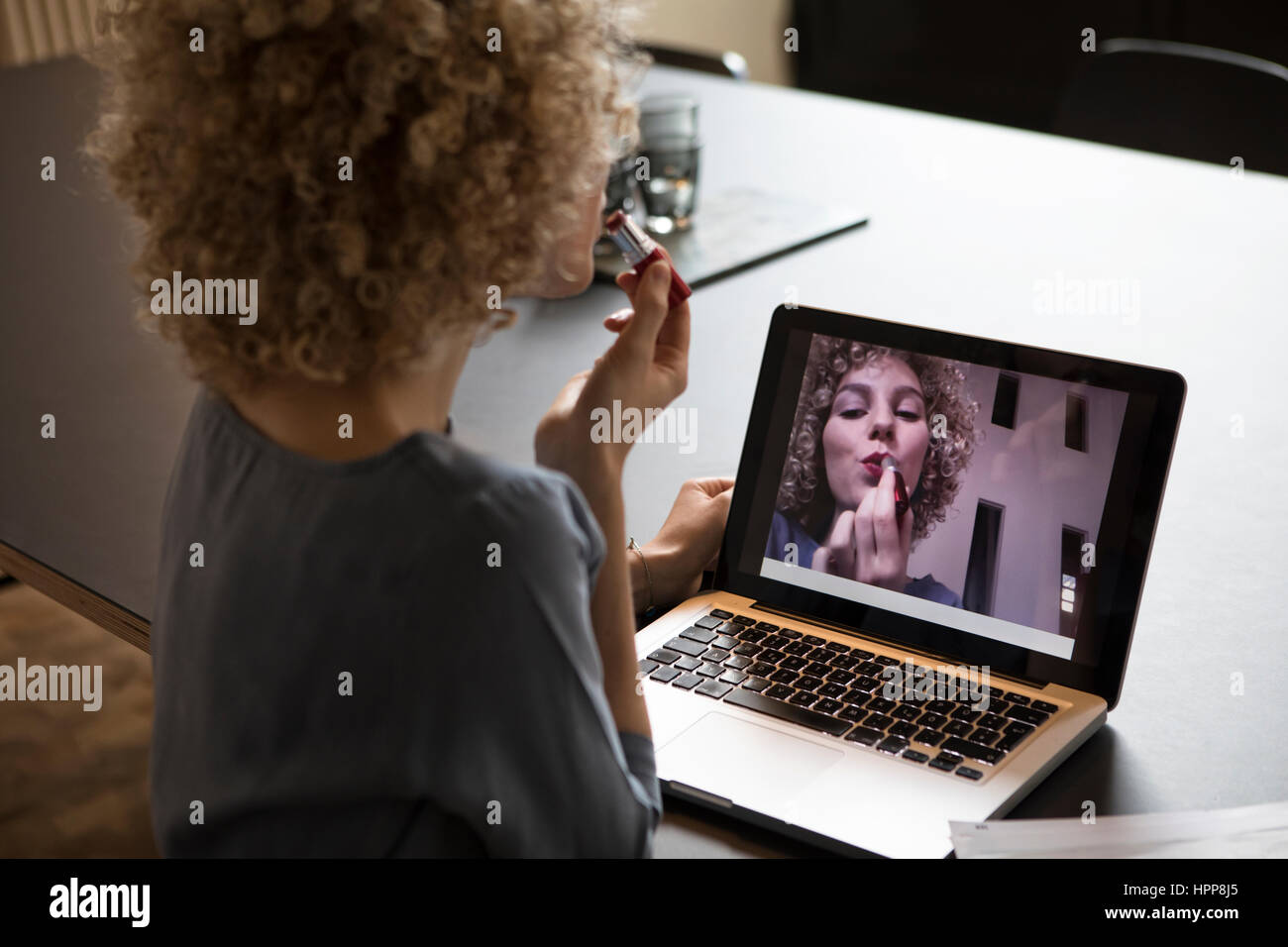 Woman in office applying make-up using laptop monitor as mirror Stock ...
