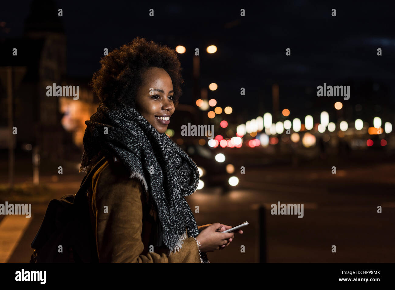 Portrait of smiling young woman with smartphone by the roadside Stock ...