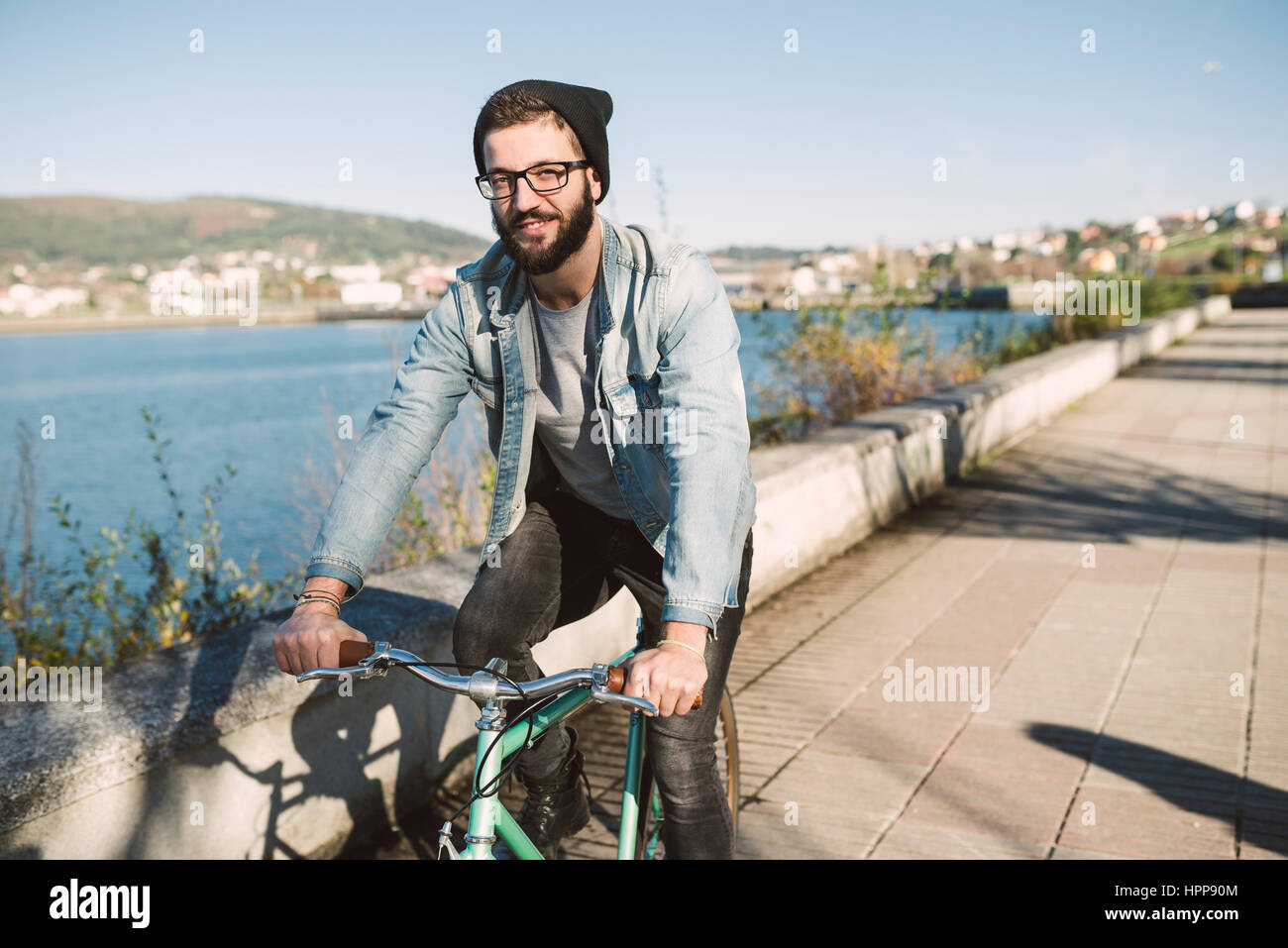 Smiling young man riding his fixie bike at the waterfront Stock Photo ...