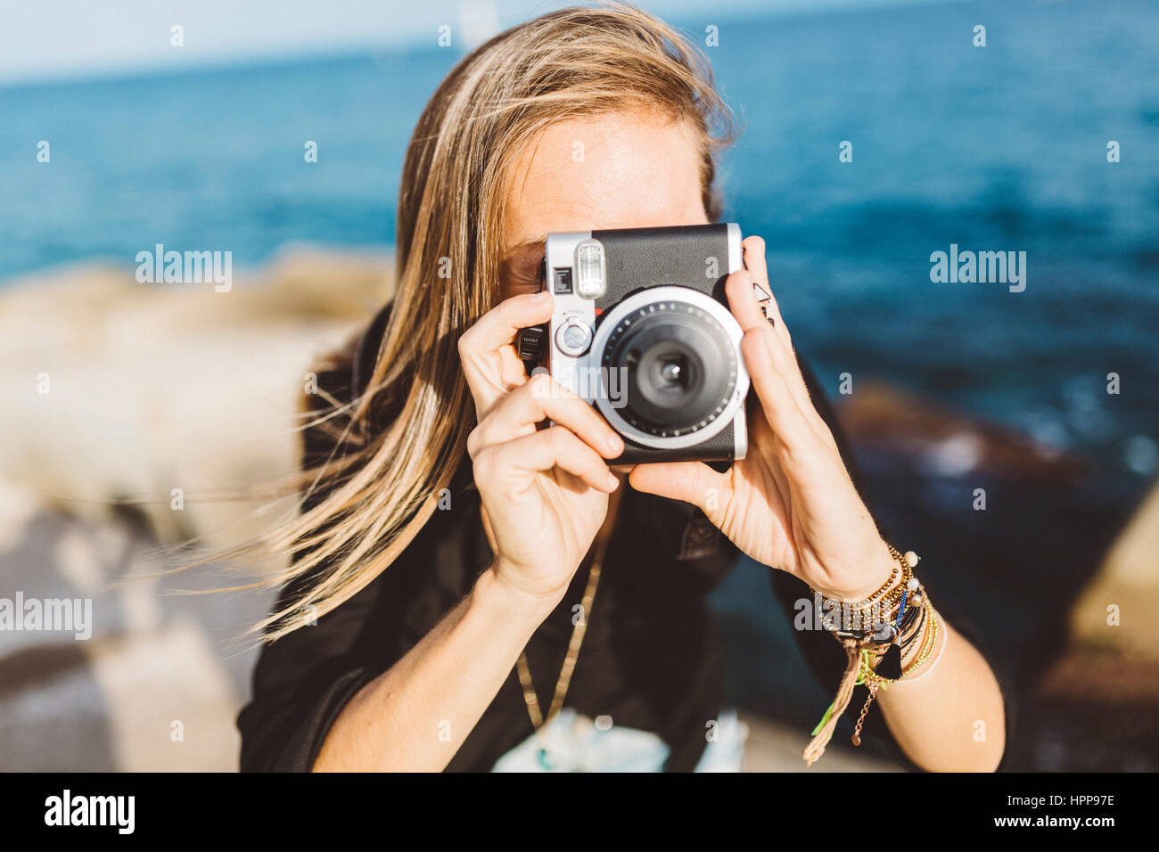 Young woman taking picture with old-fashioned camera at the seafront ...