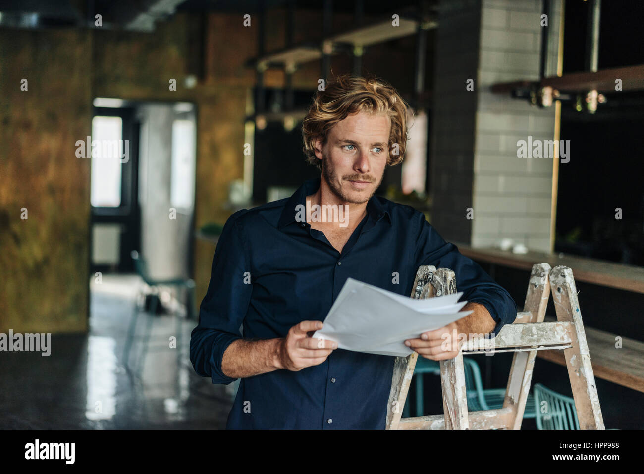 Man leaning on ladder in unfinished room Stock Photo - Alamy