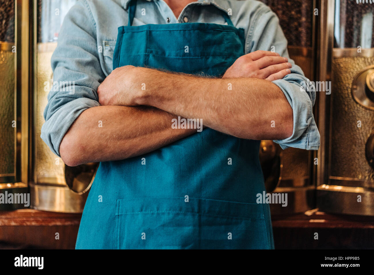 Crossed arms of a coffee roaster in his shop Stock Photo - Alamy