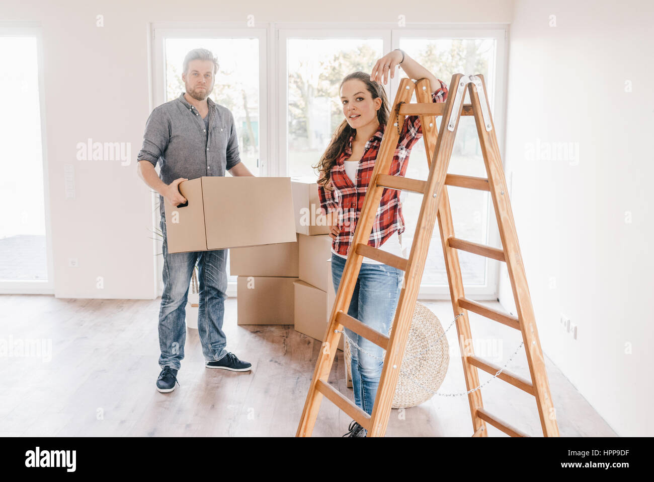 Couple moving house, carrying boxes in new home Stock Photo - Alamy