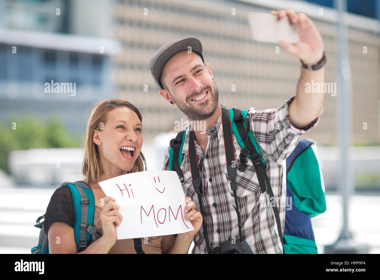 Young traveler couple taking pictures with sign saying 'Hi Mom' Stock ...