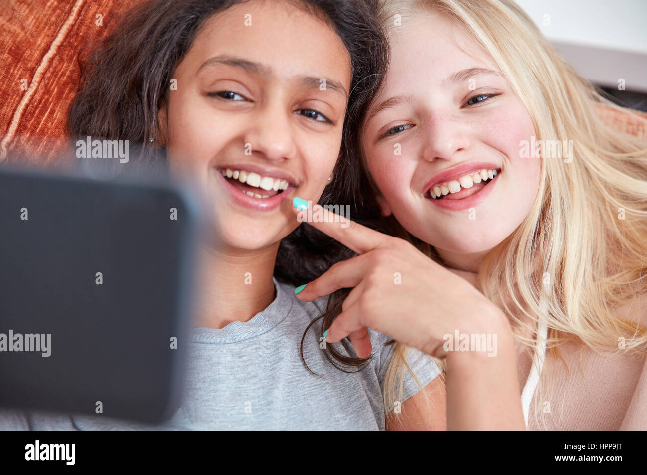 Two laughing girls looking smartphone hi-res stock photography and ...