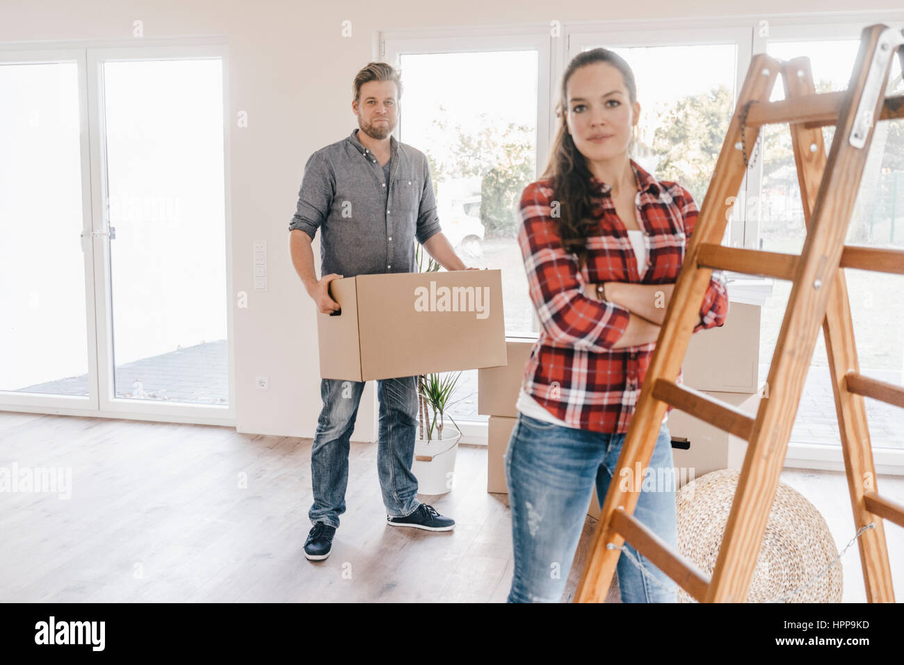 Couple moving house, carrying boxes in new home Stock Photo - Alamy