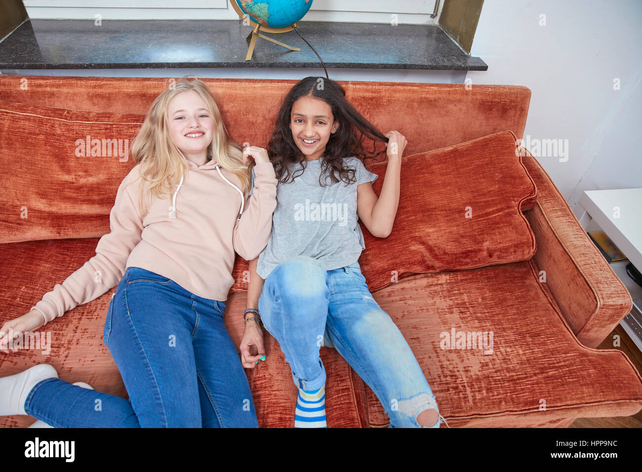 Two happy girls relaxing on couch Stock Photo - Alamy