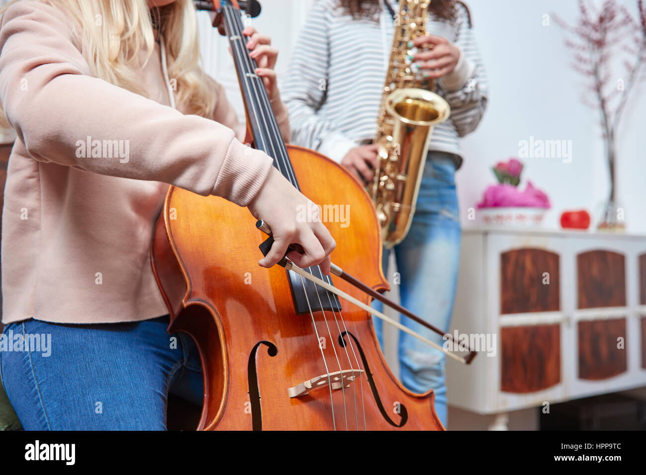 Two girls playing cello and saxophone together Stock Photo - Alamy