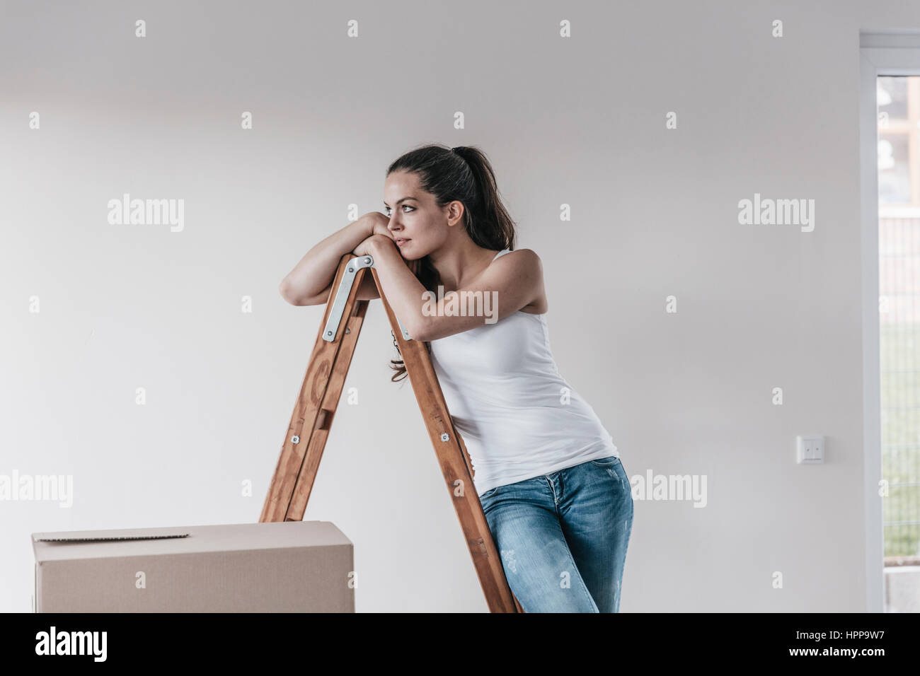 Mature woman standing in her new home, leaning on ladder Stock Photo ...
