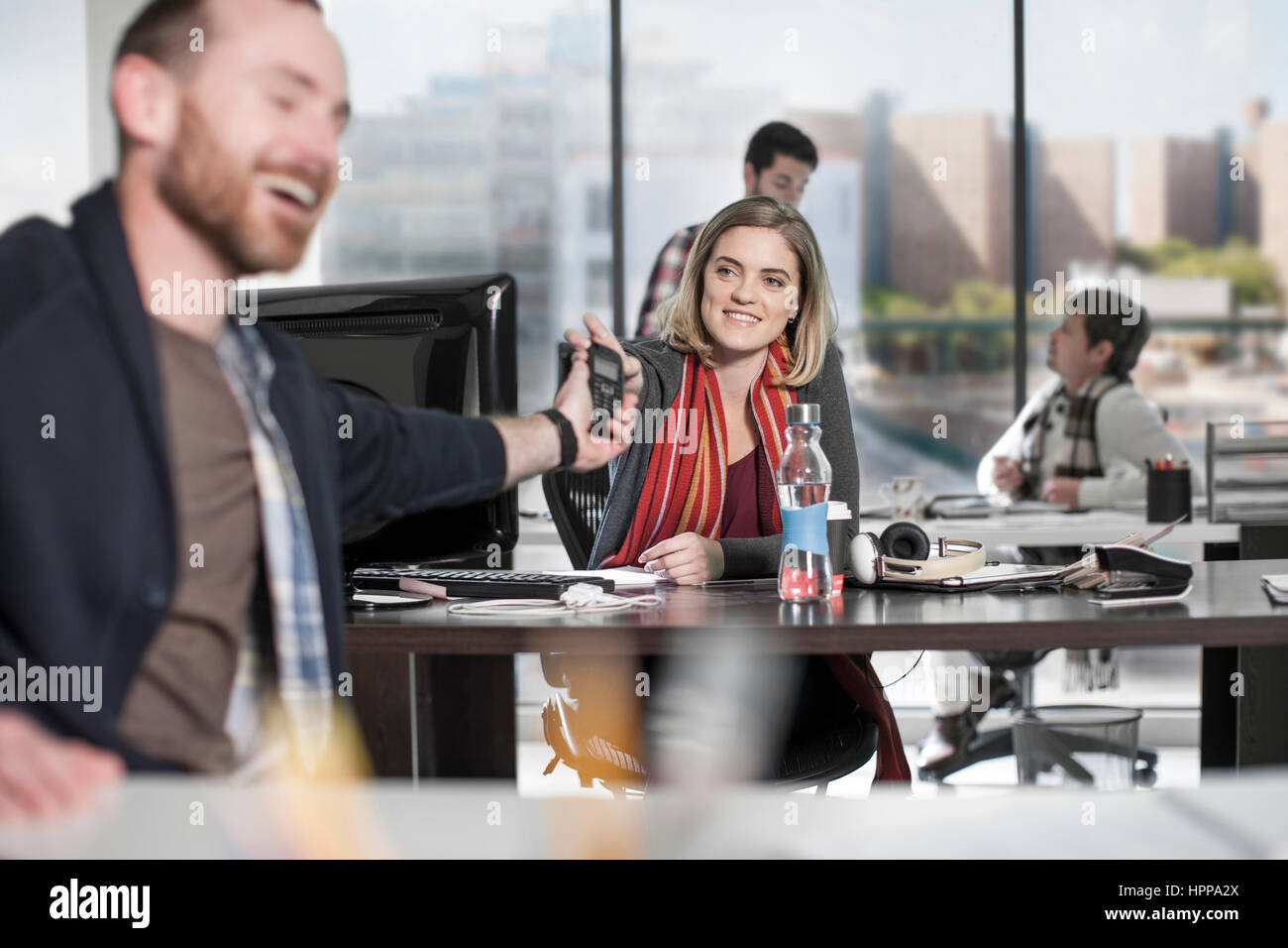 Man handing over telephone to colleague in office Stock Photo - Alamy
