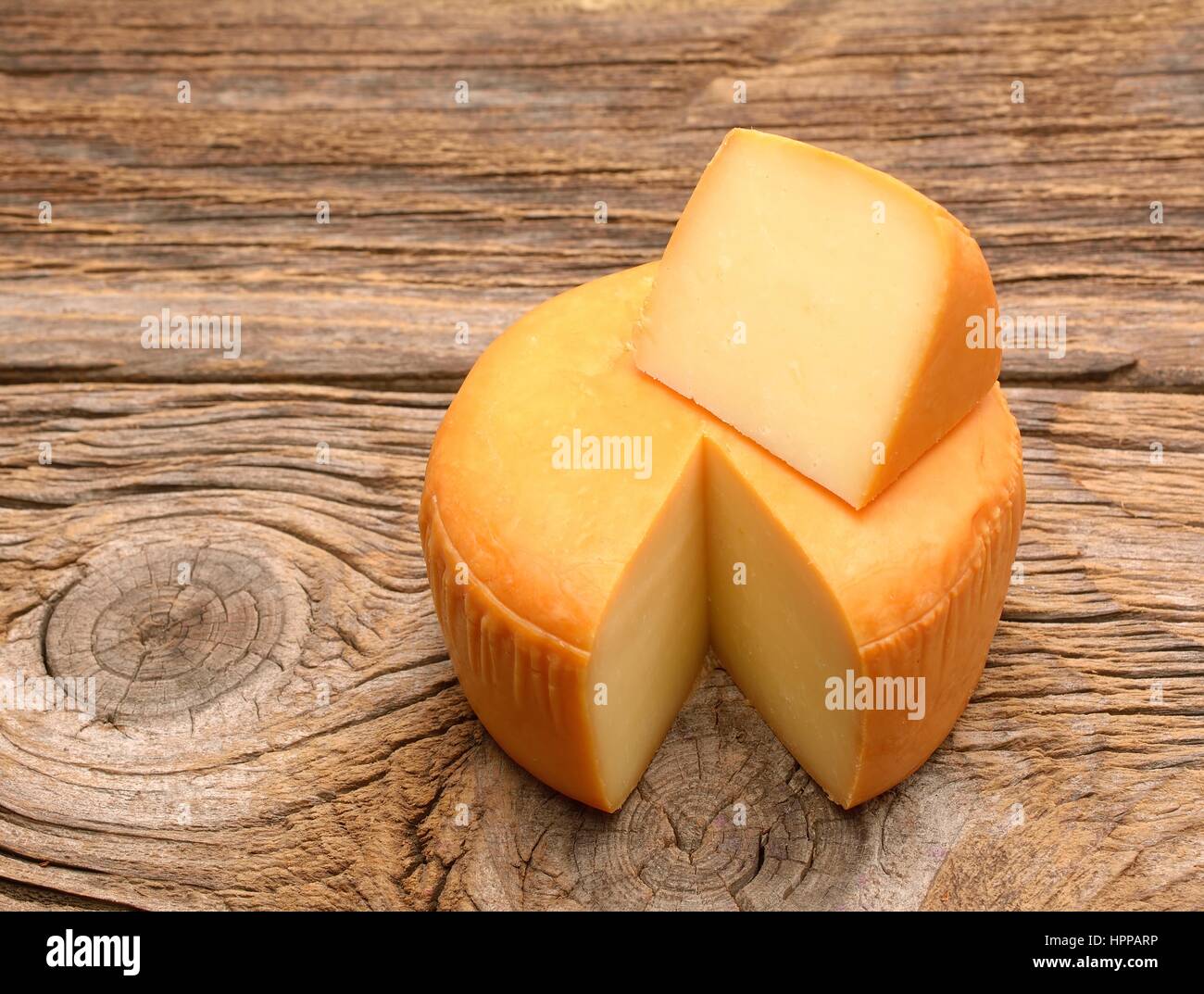 Cheese wheel on wooden table Stock Photo - Alamy