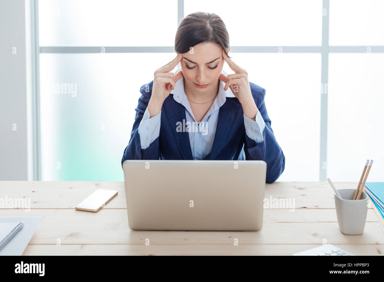 Exhausted businesswoman in her office with head in hands, she is having ...