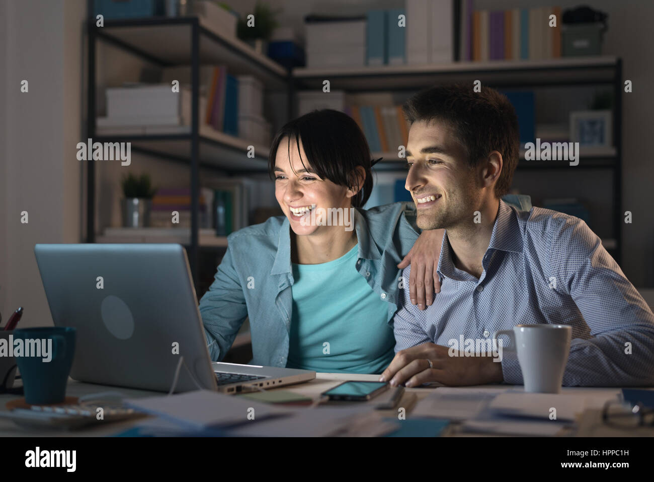 Happy smiling married couple at home using a laptop, connecting to ...