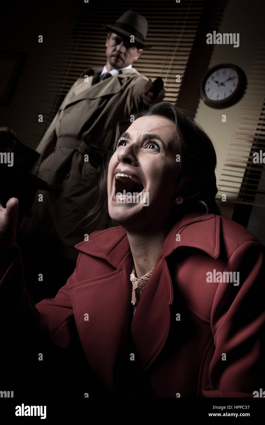 Detective standing in the dark and pointing a gun to a screaming woman ...