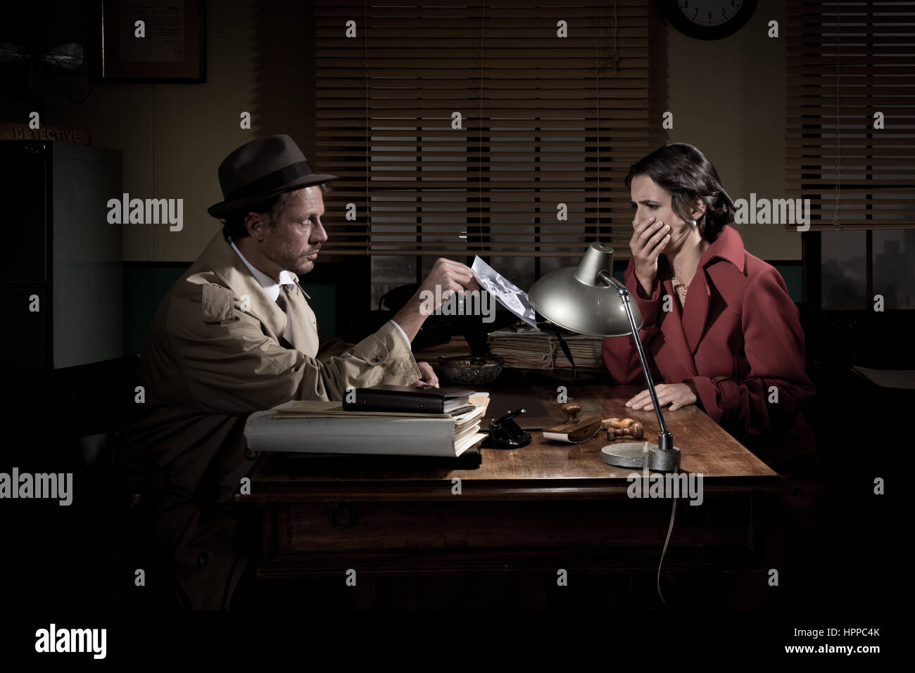 Handsome detective at office desk showing a picture to a young woman ...