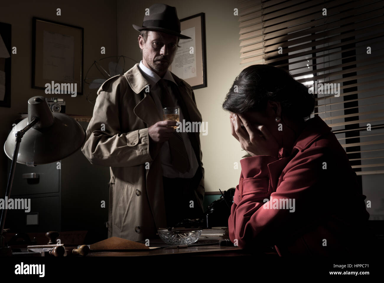 Desperate woman crying head in hands and confident detective standing ...