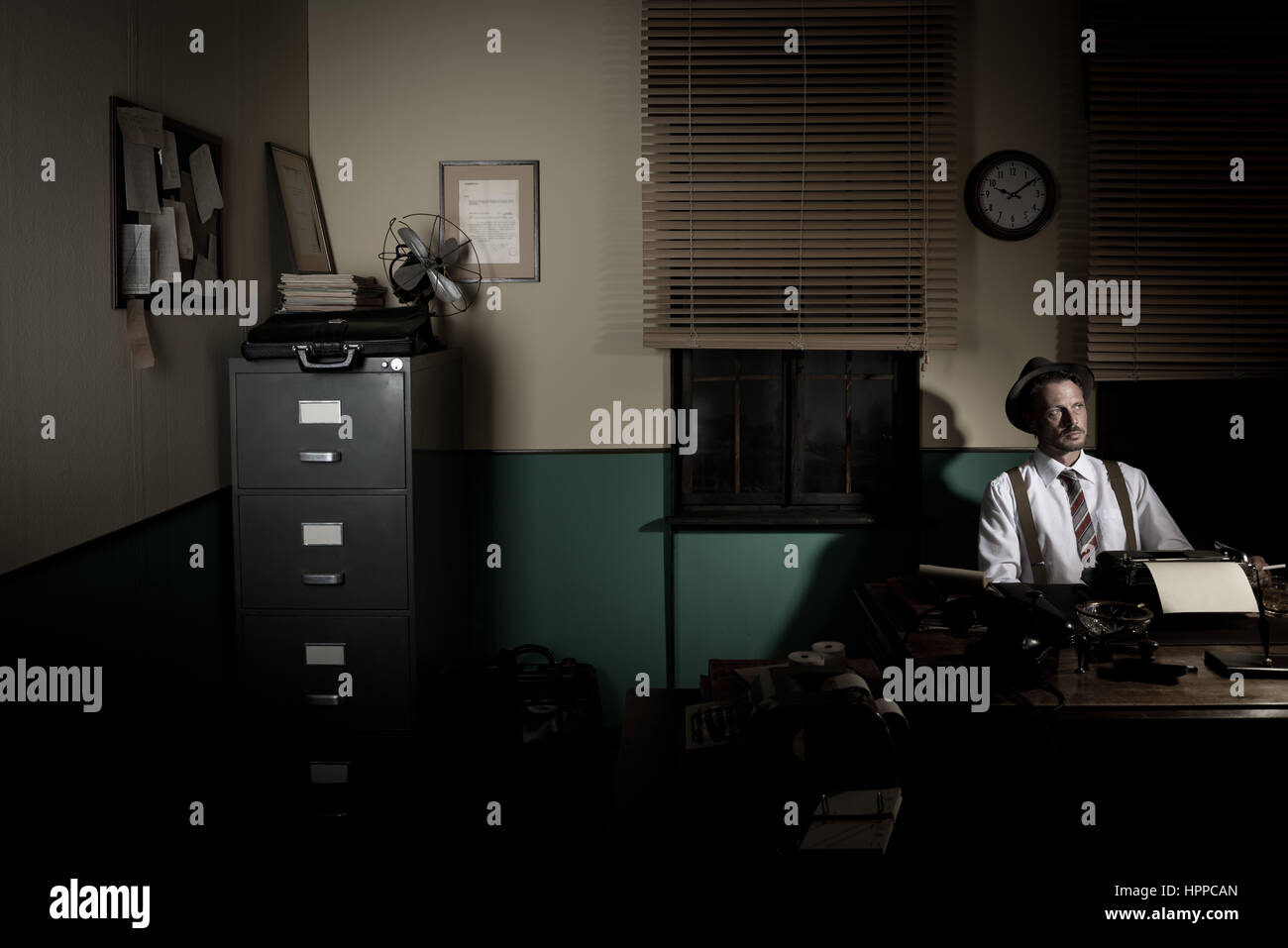 1950s style reporter working late at night sitting at his desk Stock ...
