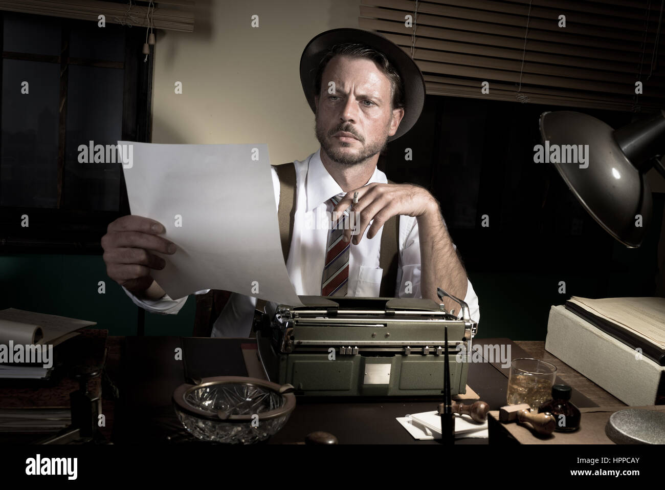 1950s reporter working late at night and proofreading his work Stock ...