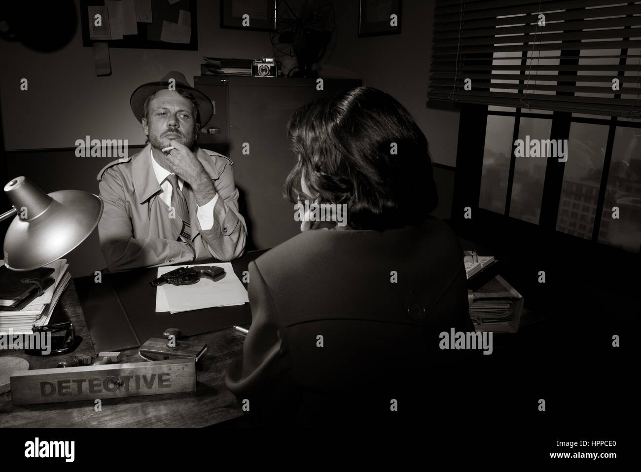 Handsome detective at office desk interviewing a young woman, 1950s ...