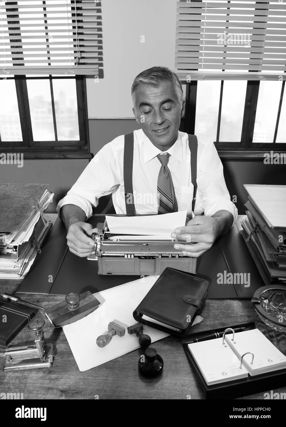 Professional handsome reporter working at office desk, 1950s style ...