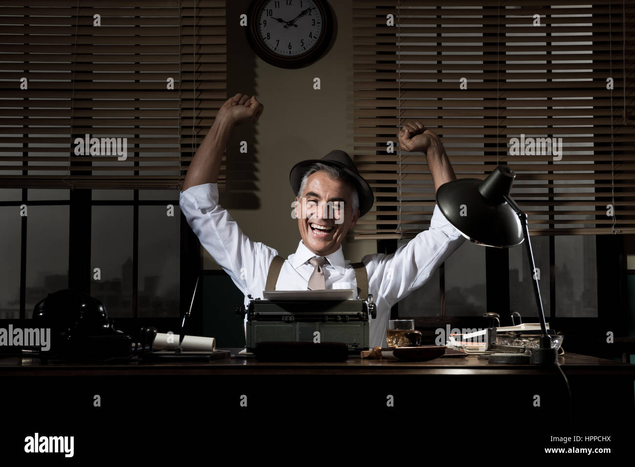 Cheerful successful reporter working at office desk with fists raised ...