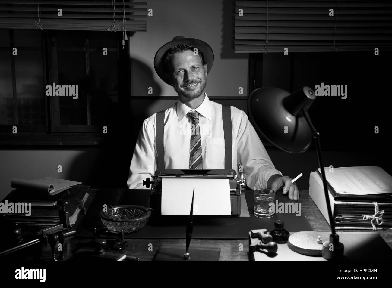Smiling retro reporter having a cigarette break at desk Stock Photo - Alamy