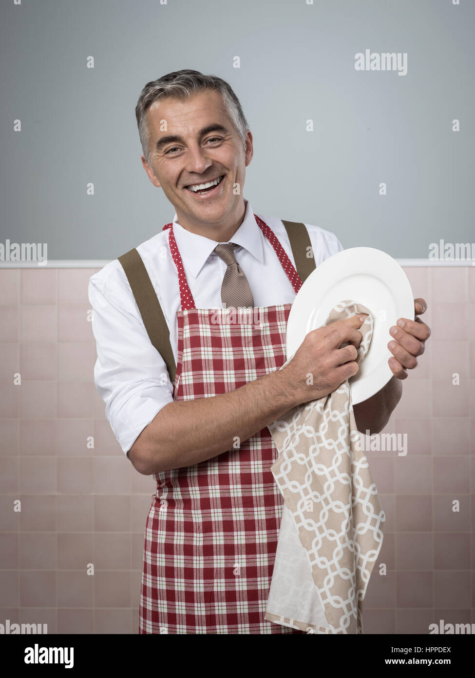 Vintage smiling man in apron doing household chores cleaning dishes ...