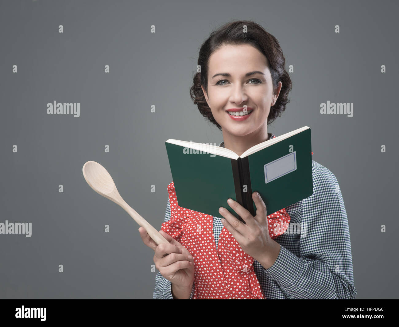 Smiling vintage woman holding an open cookbook and a wooden spoon Stock ...