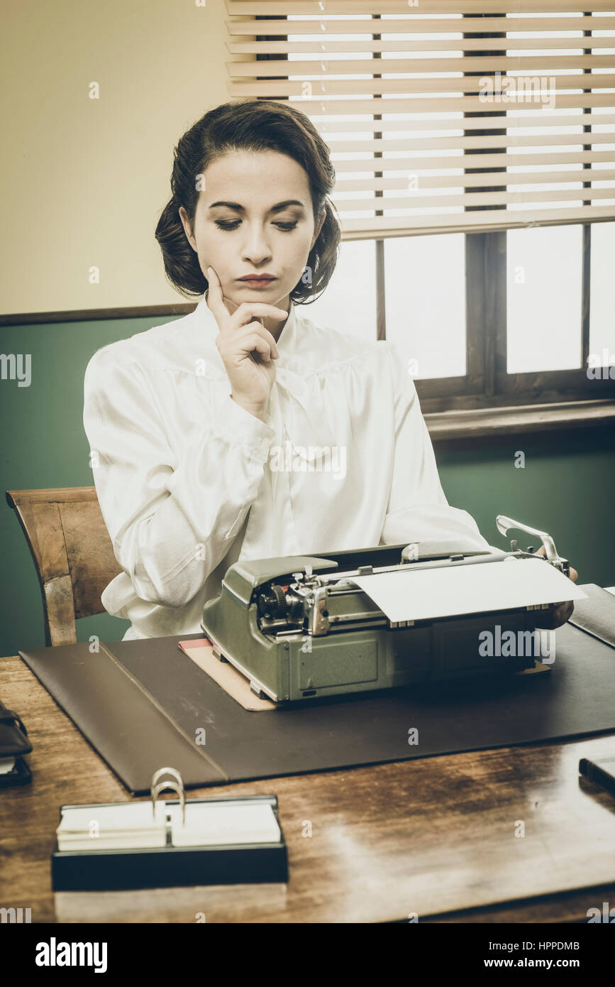 Pensive vintage woman with hand on chin, typing on typewriter and ...