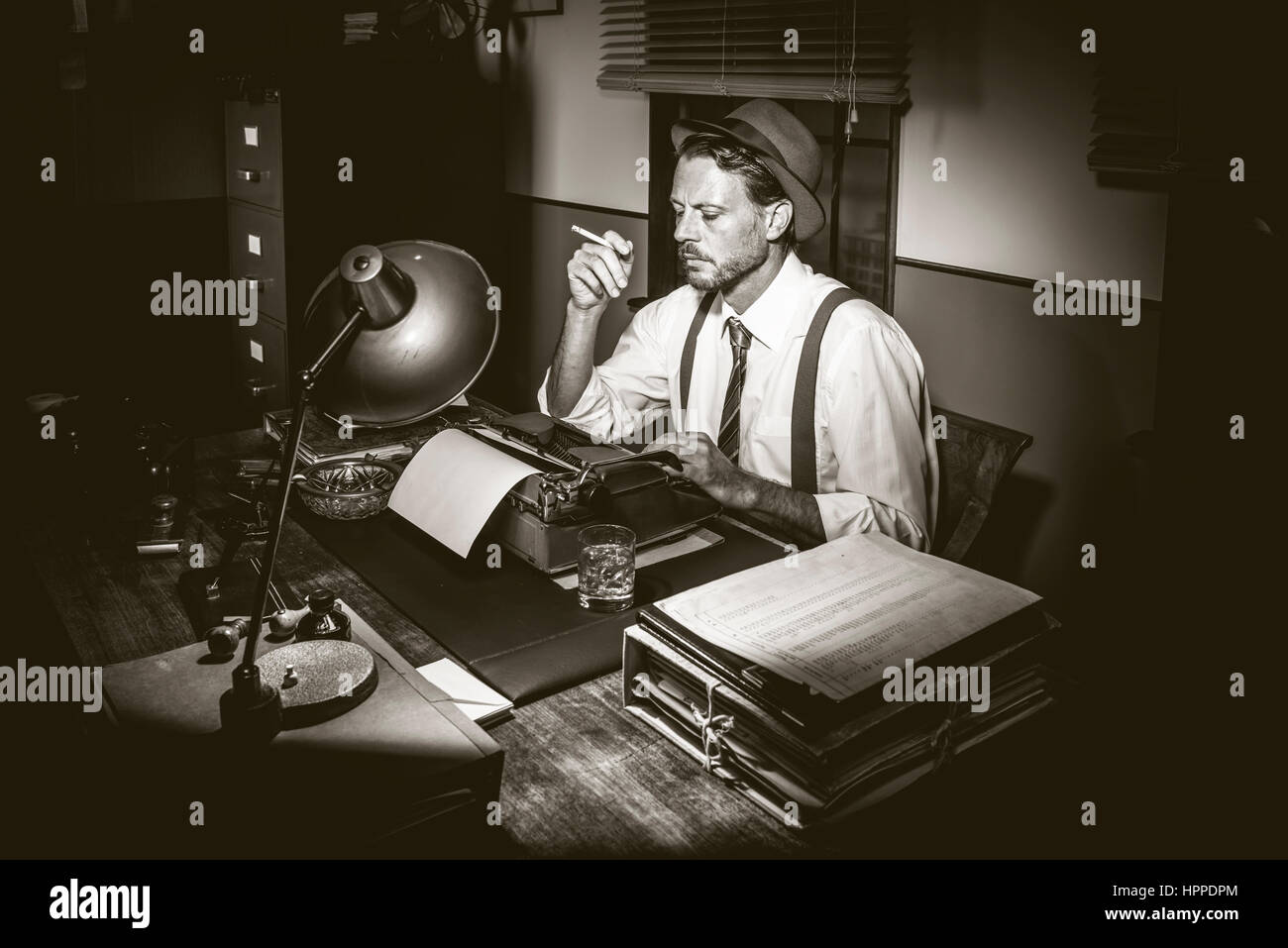Retro reporter working late typing on a typewriter and smoking a ...