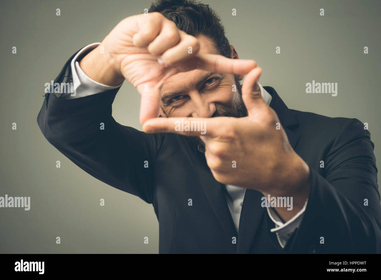 Attractive smiling man framing eyes with fingers, focus concept Stock ...